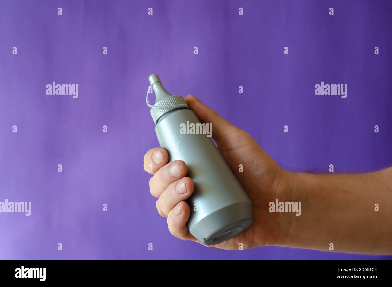 Male hand and gray plastic bottle of syrup. The man is holding a new ...
