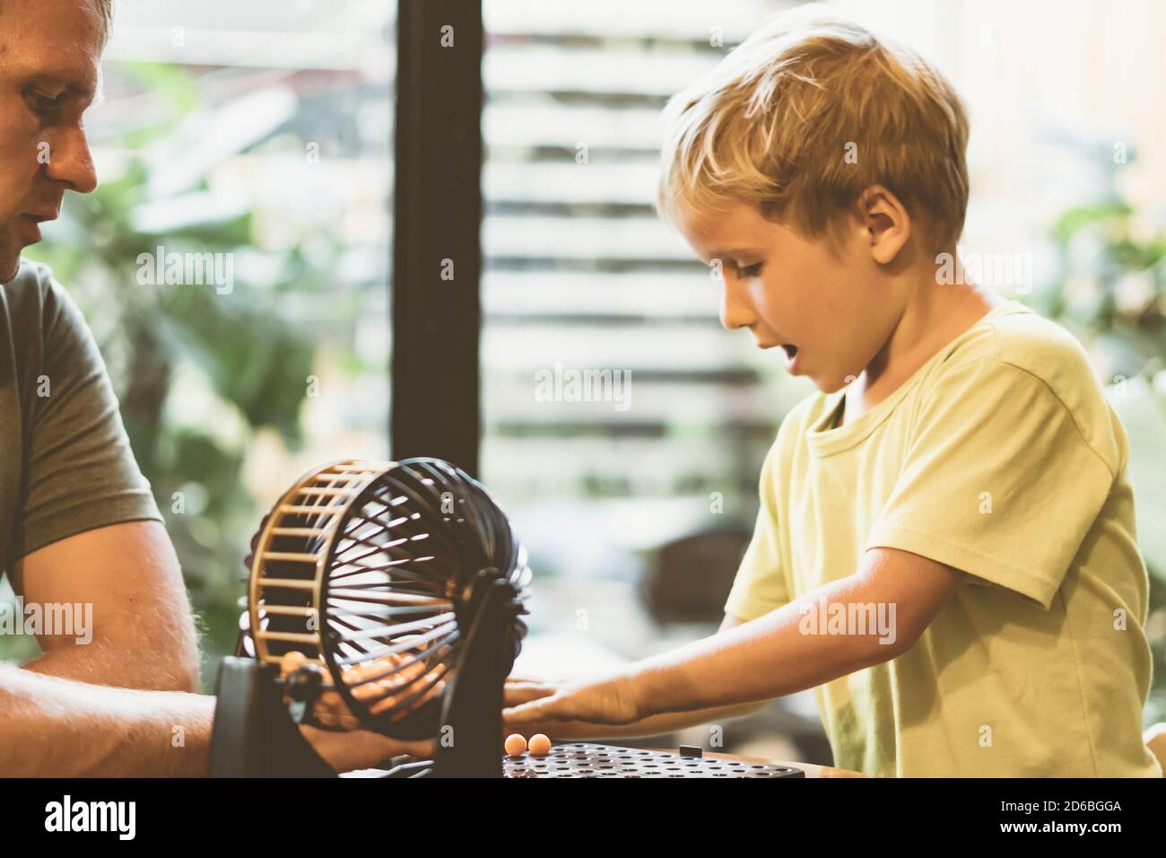 Father blond son boy play lotto, round sphere spins with small orange ...