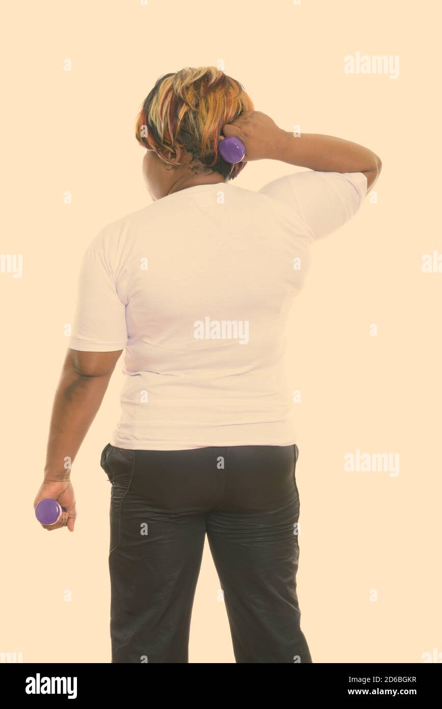 Back view of fat black African woman exercising with dumbbells ready ...