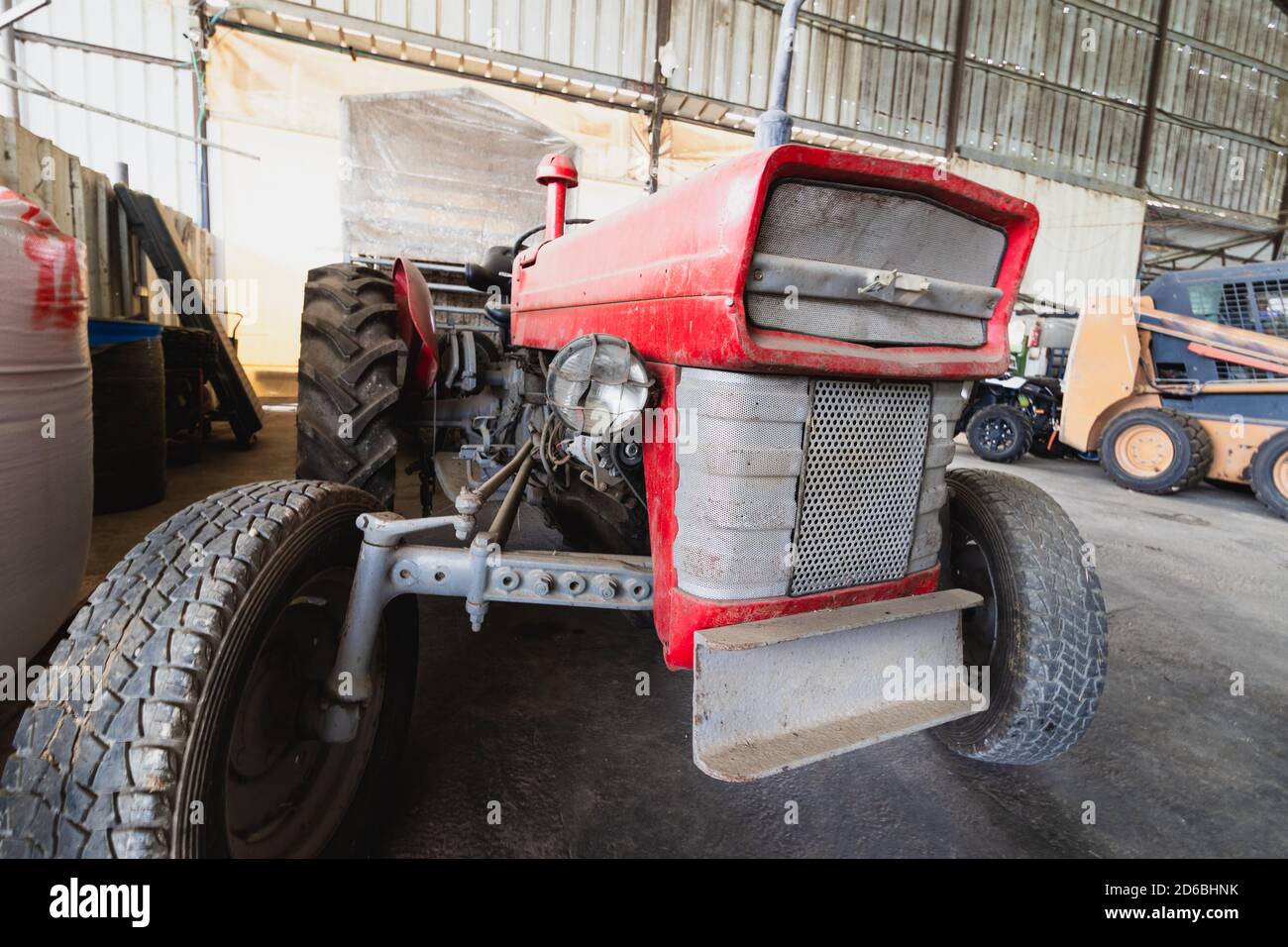 An old red tractor stands inside a tin barn Stock Photo - Alamy