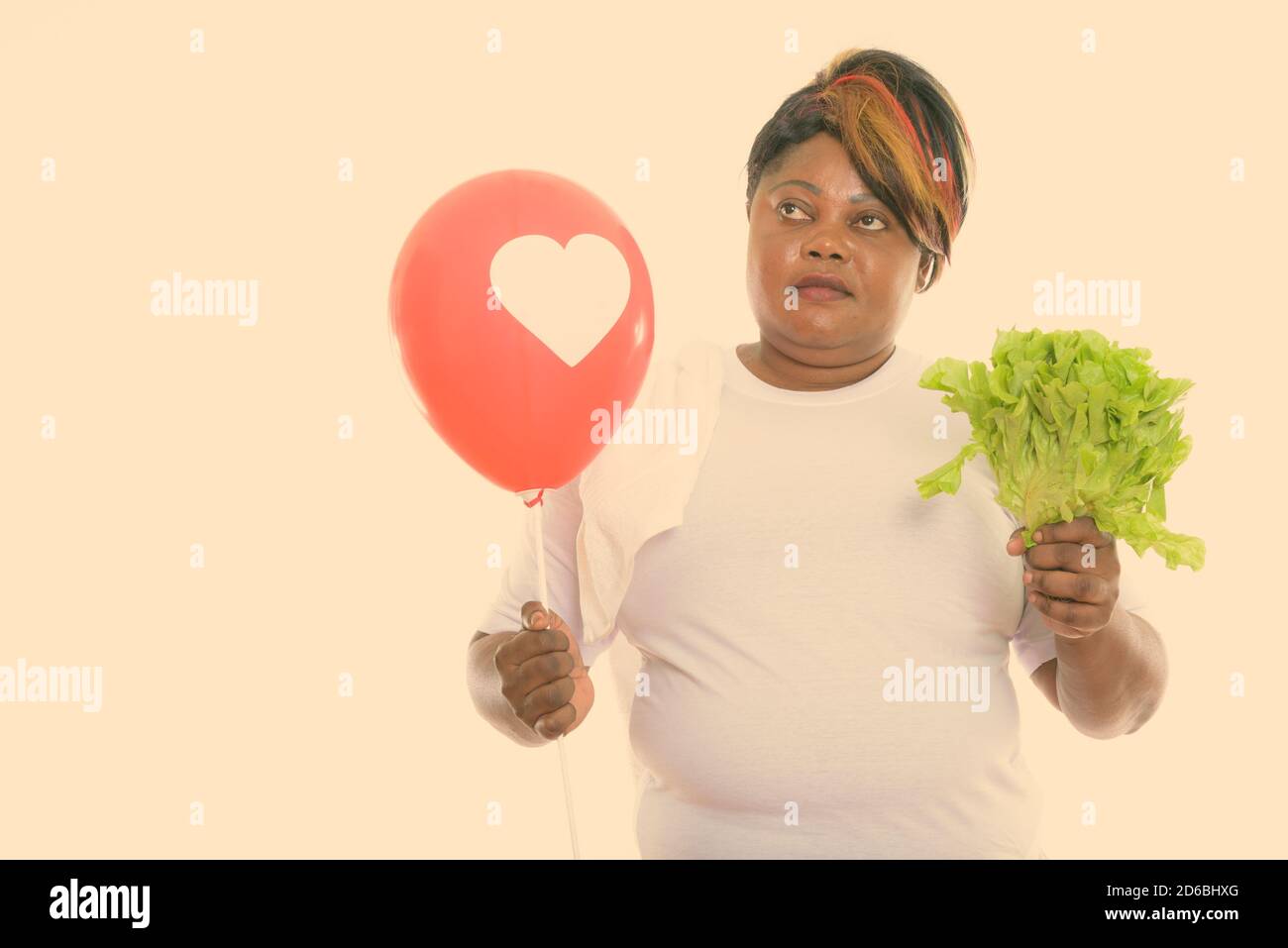 Studio shot of fat black African woman thinking while holding lettuce ...