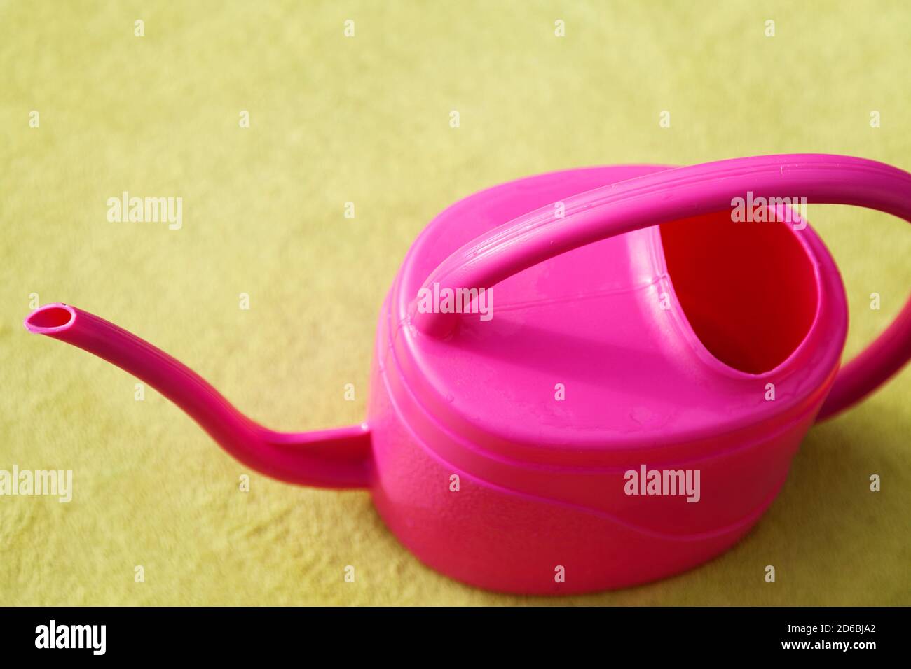 a pink watering can on green background Stock Photo - Alamy