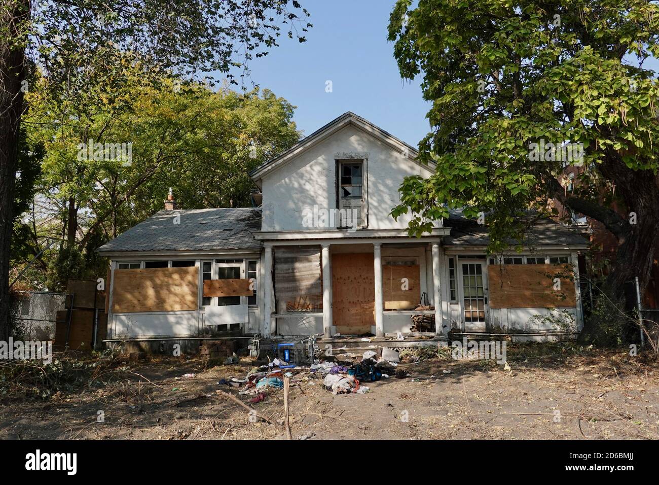 An abandoned boarded up house with trash all around Stock Photo - Alamy
