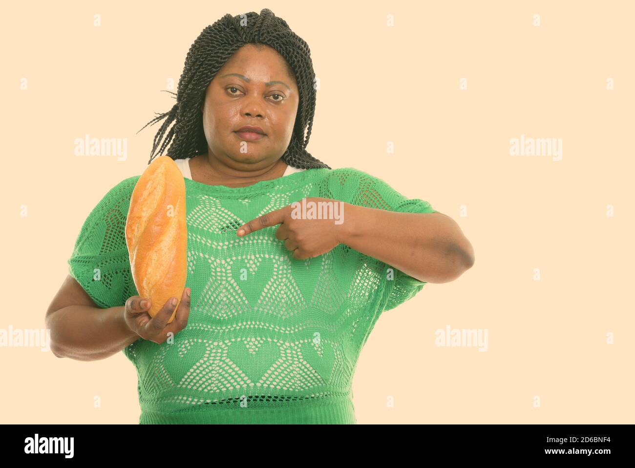 Studio shot of fat black African woman holding and pointing at bread ...
