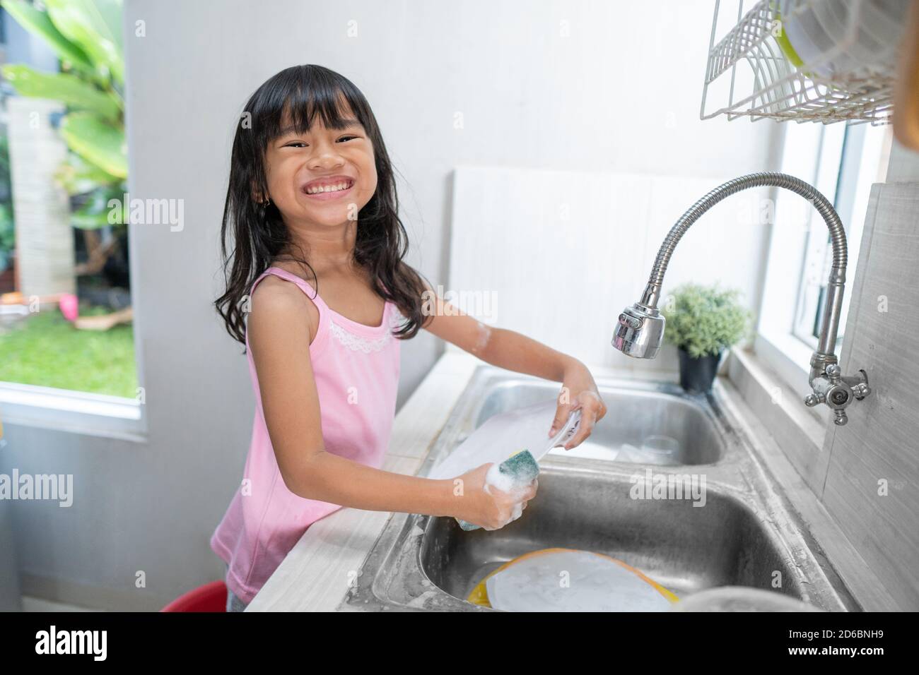 kid washing the dishes. helpful young girl doing clean up at home Stock ...