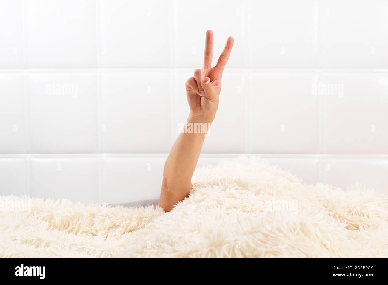 Female hand show a v sign in a white bed, a wonderful start to a new ...