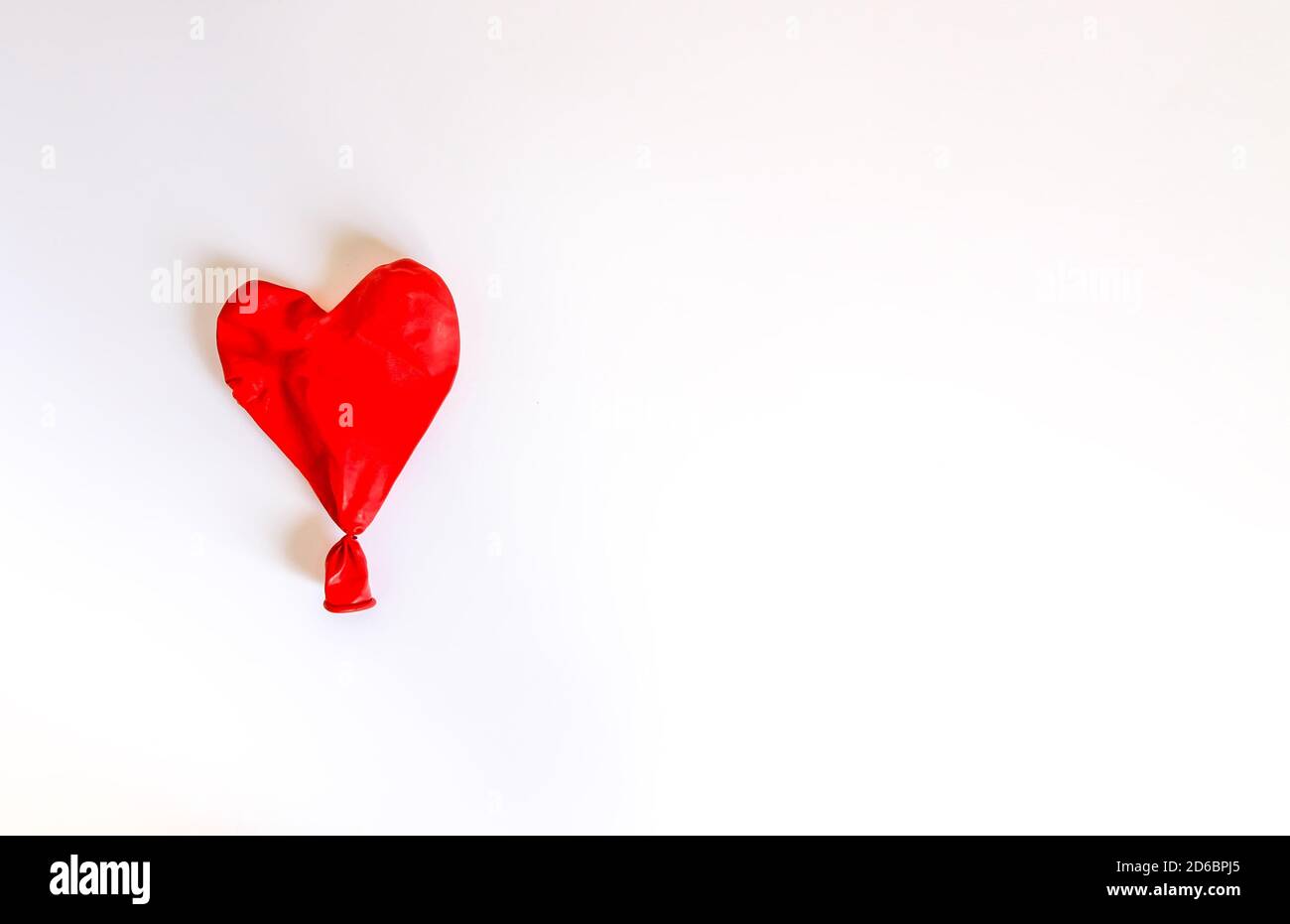 Red heart deflated balloon on white background Stock Photo - Alamy