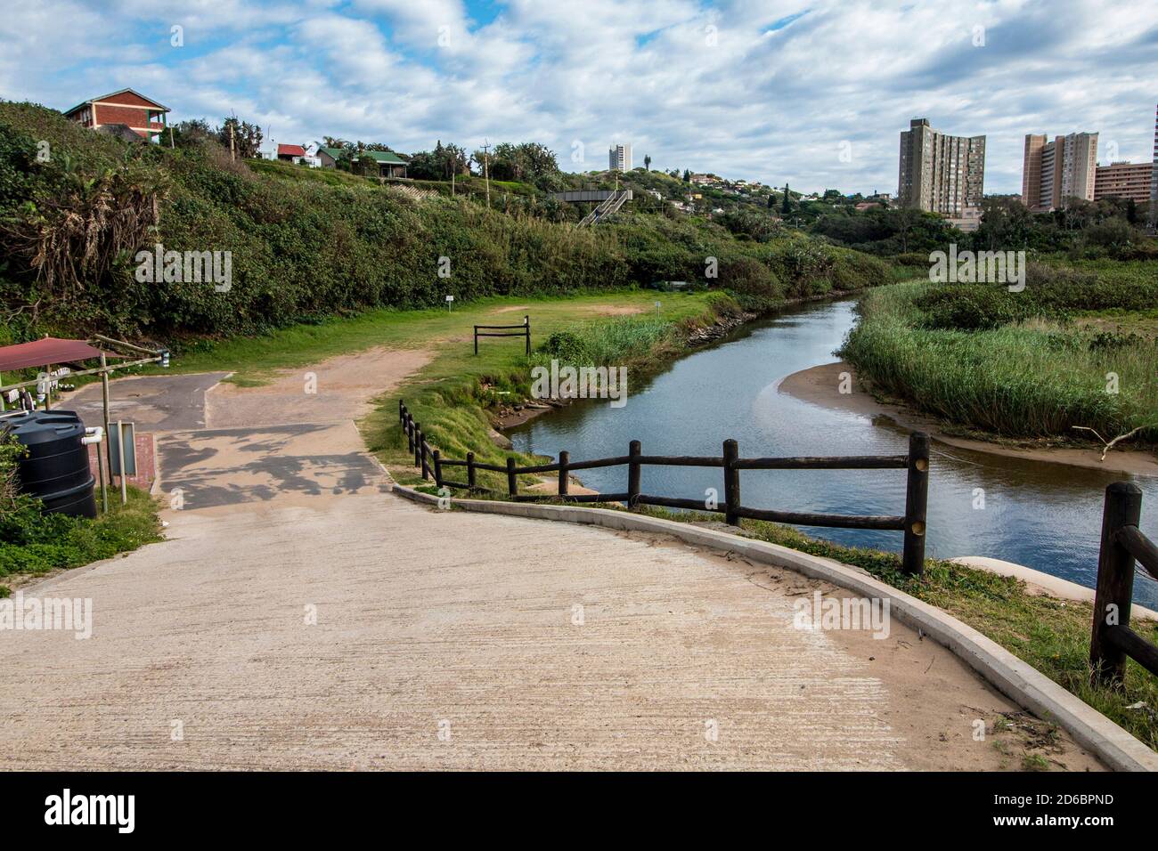 Cement pathway leading to side of river with tall buldings in ...
