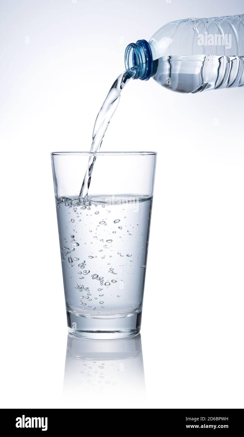 Pour bottled water into a clear glass placed on a white background Stock Photo - Alamy