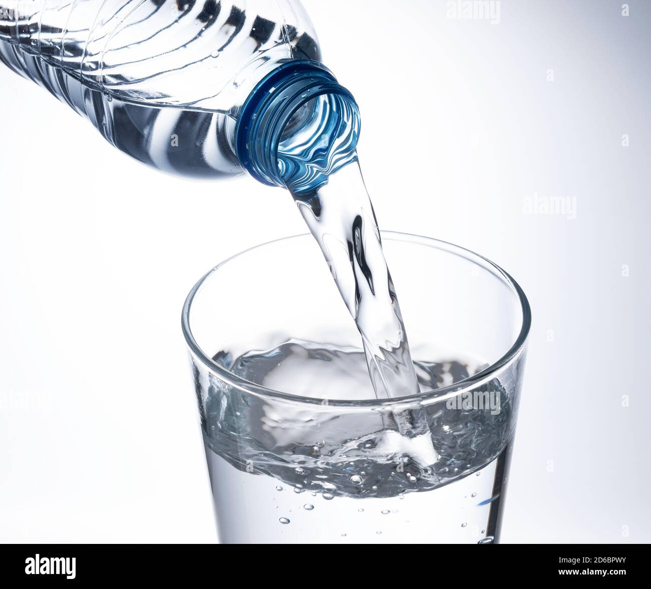 Pour bottled water into a clear glass placed on a white background ...