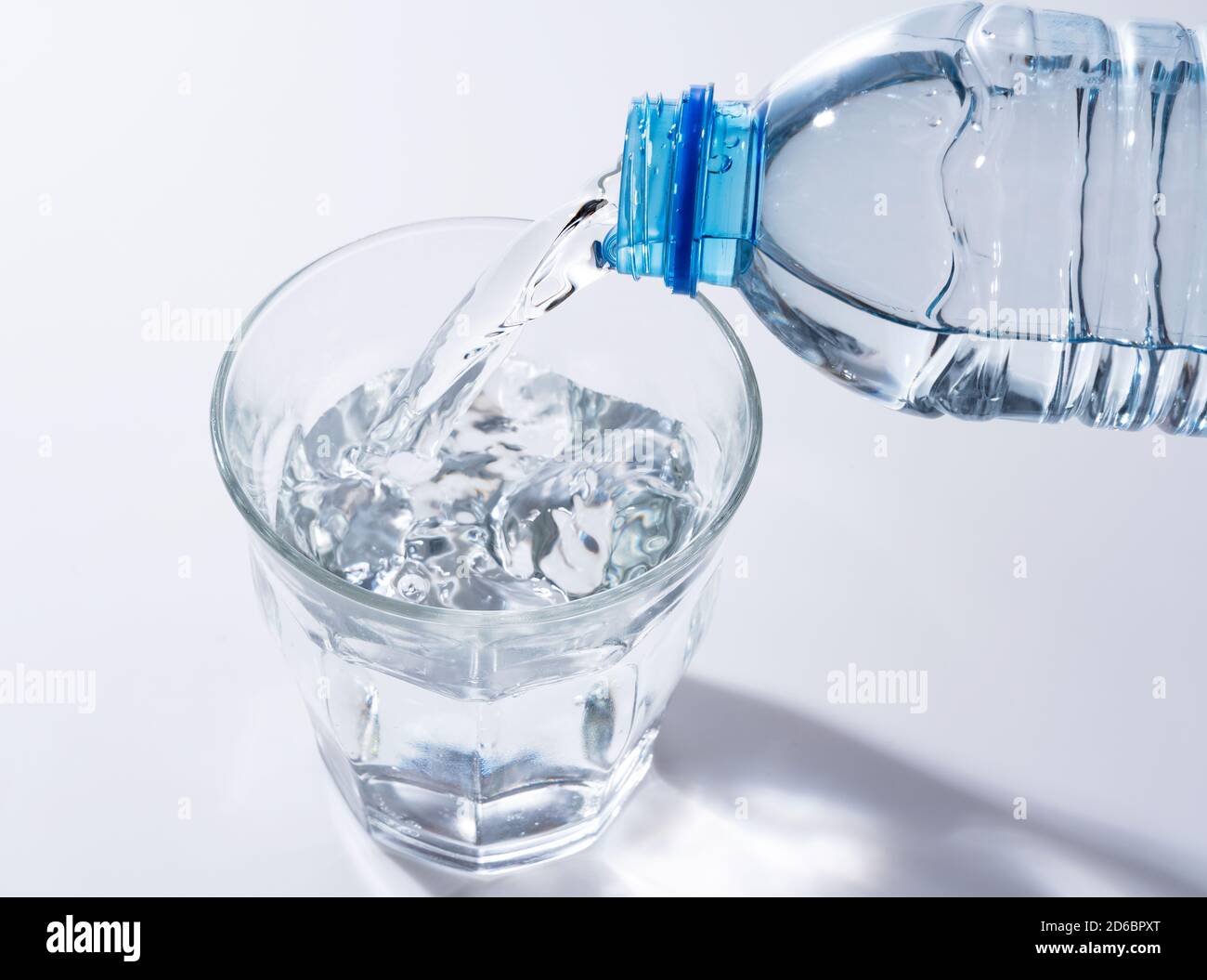 Pour bottled water into a clear glass placed on a white background ...