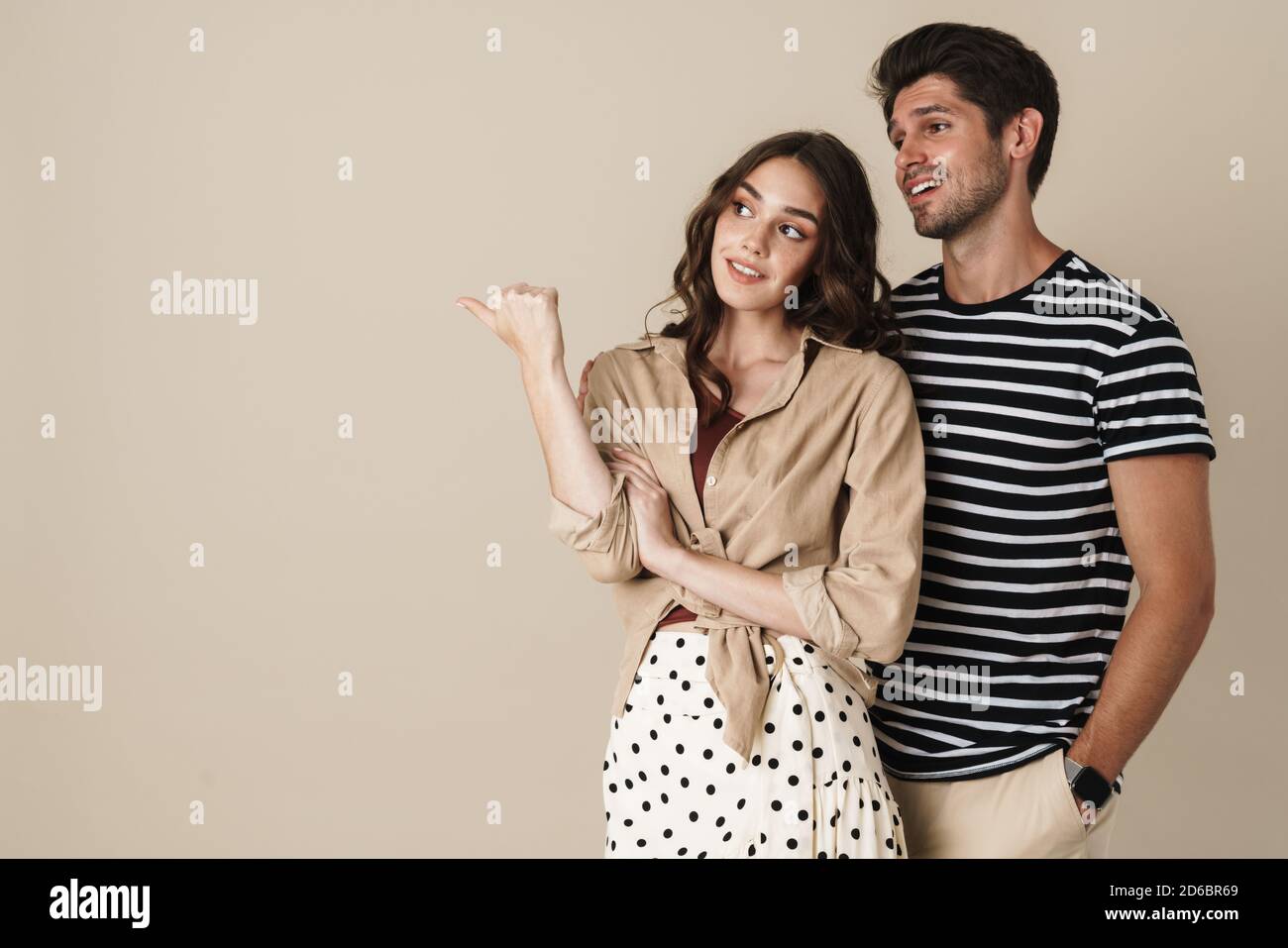 Image of cheerful beautiful couple pointing finger aside and smiling ...