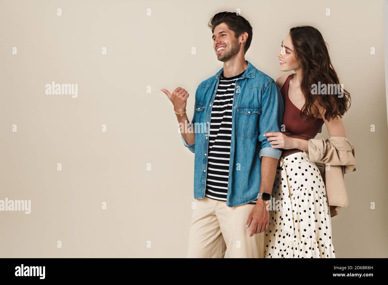 Image of cheerful beautiful couple pointing finger aside and laughing ...