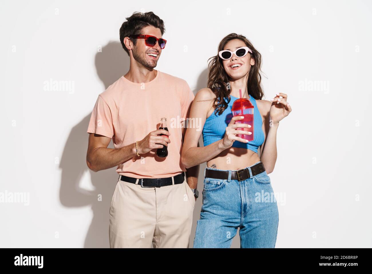 Image of cheerful beautiful couple laughing while drinking beverages ...