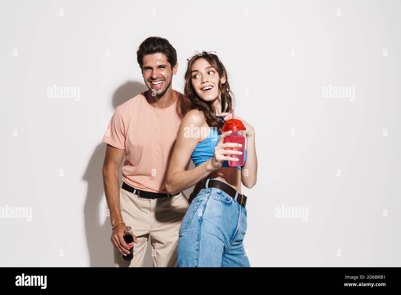 Image of excited beautiful couple laughing while drinking beverages ...