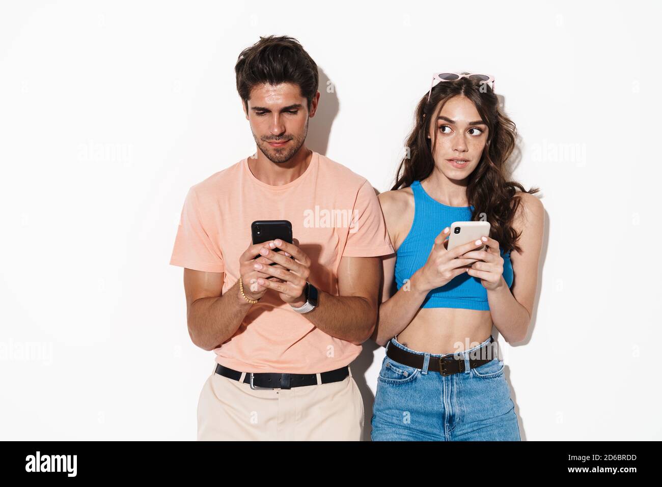 Image of focused young couple posing while using cellphones isolated ...
