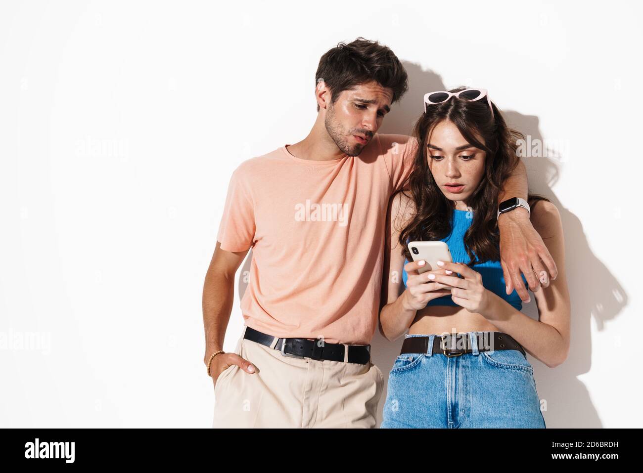 Image of attractive confused couple hugging while using cellphone ...