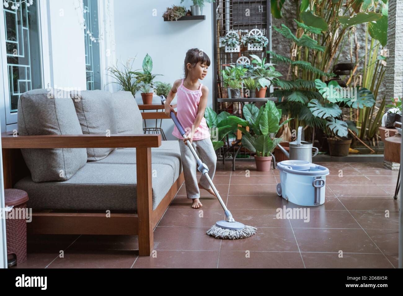 Cute Asian girl helping with housekeeping cleaning floor with a wet ...