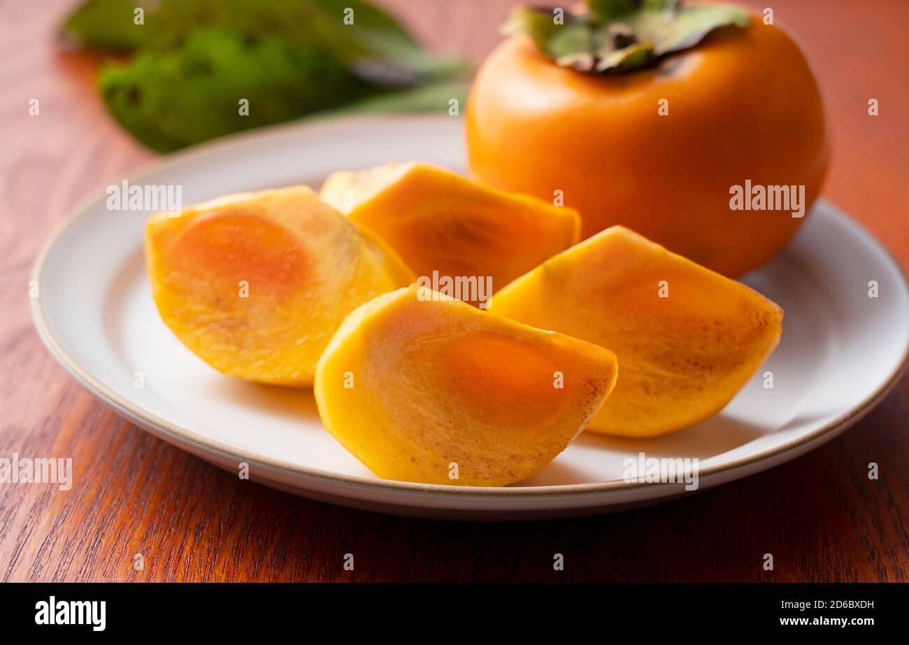 Cut Japanese persimmons on a plate. Japanese style image Stock Photo ...