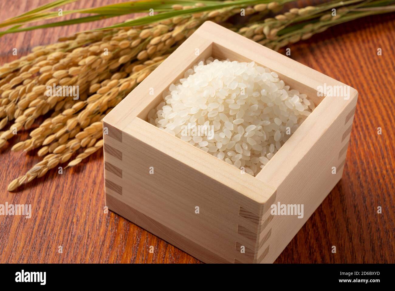 Rice and ears of rice in a Japanese Masu box set against a wooden ...