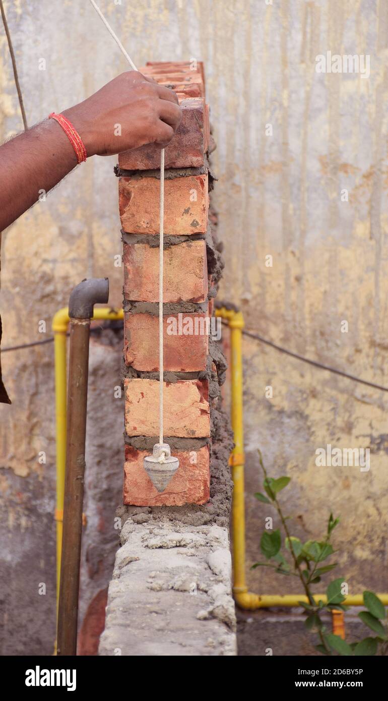 Indian professional construction worker measuring brick wall for ...