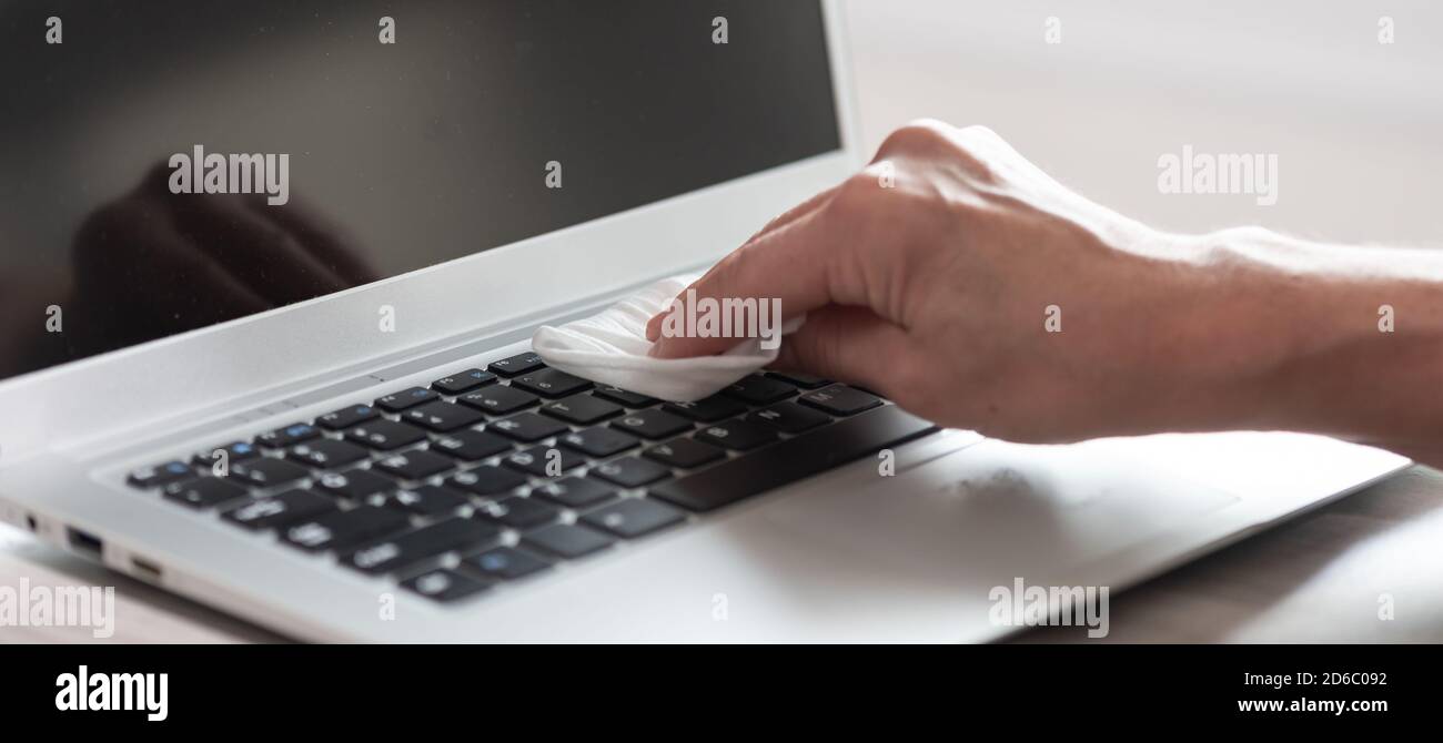 Woman disinfecting laptop keyboard with antibacterial wipe; prevention ...