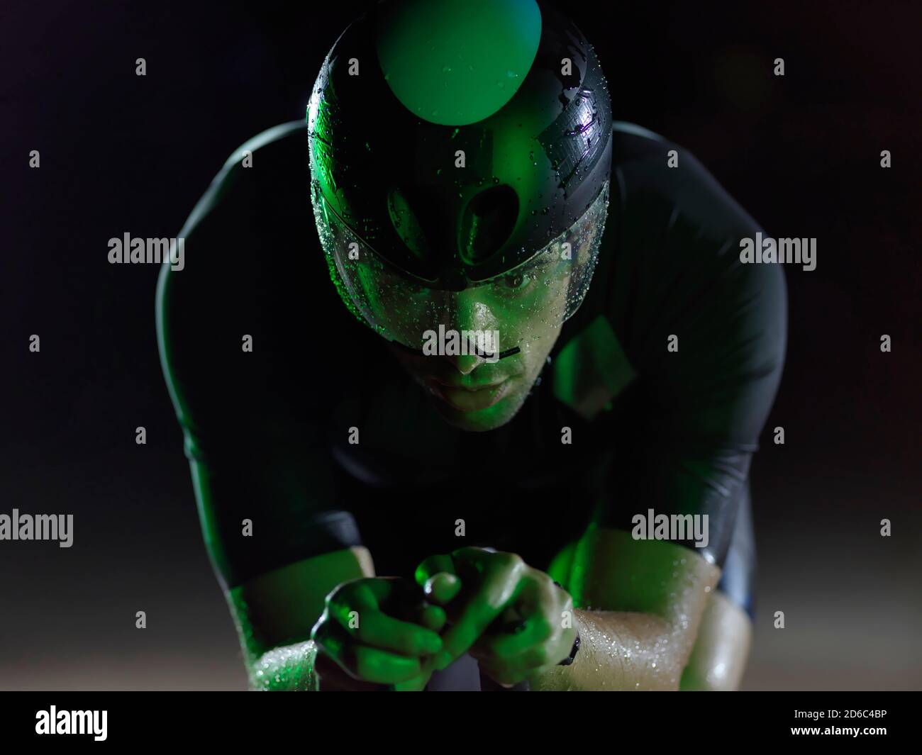 triathlon athlete riding professional racing bike at night neon gel ...