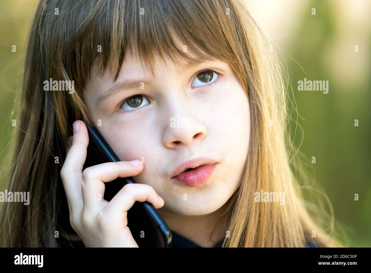 Portrait of pretty child girl with long hair talking on cell phone ...