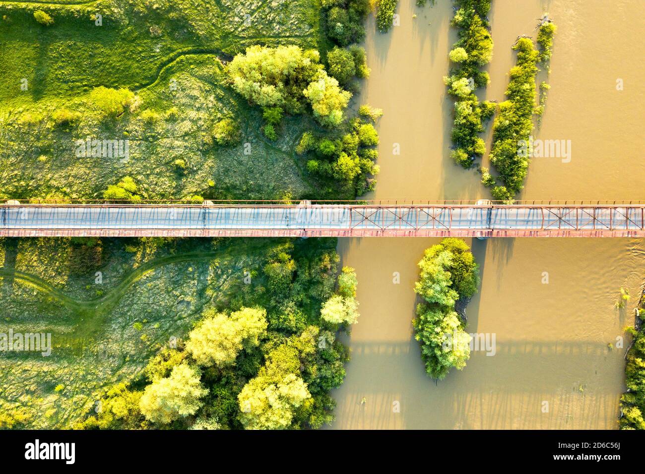 Aerial view of a narrow road bridge stretching over muddy wide river in ...