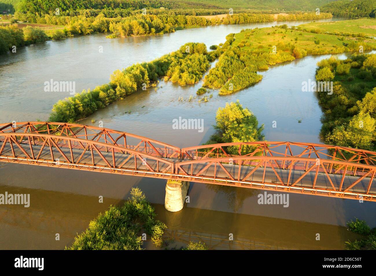 Aerial view of a narrow road bridge stretching over muddy wide river in ...