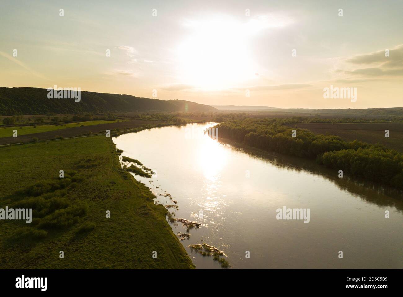 Aerial view of bright river flowing through green meadows in spring ...