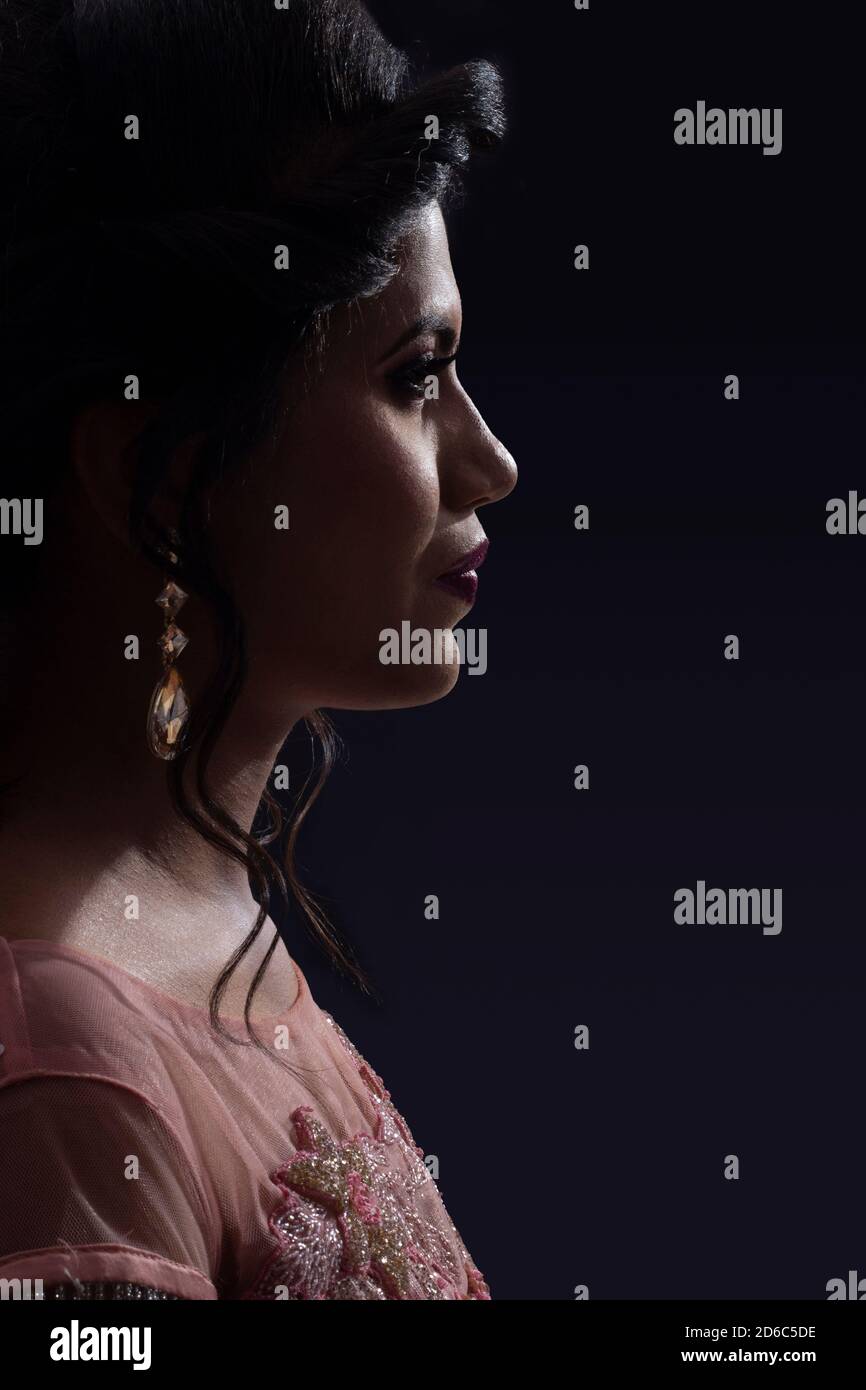 Indian model in pink dress and jewelry. Side profile of face. Black ...