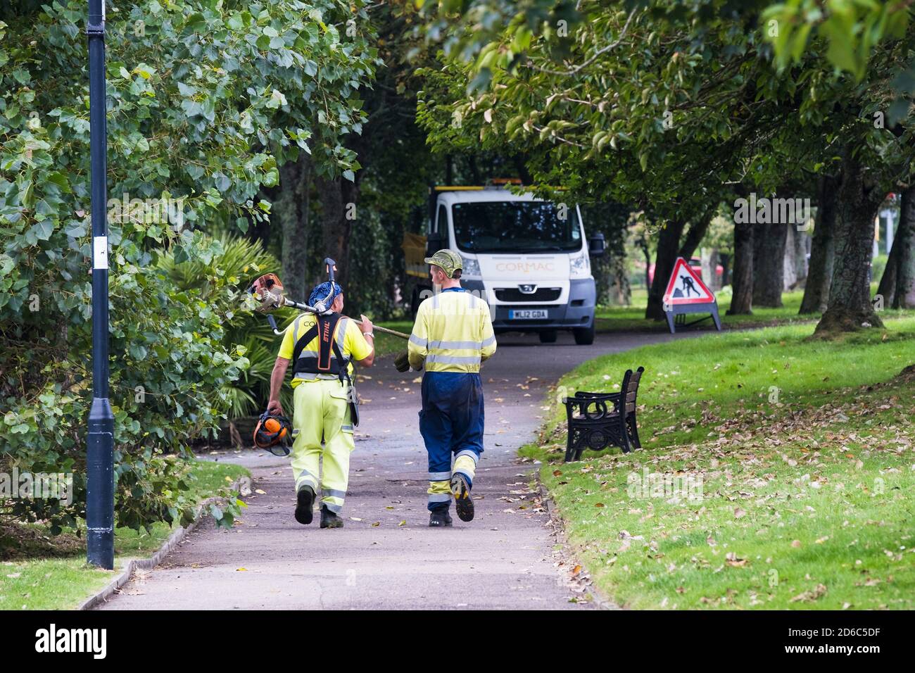 A rear view of two Cormac workers wearing hiviz clothing and walking ...