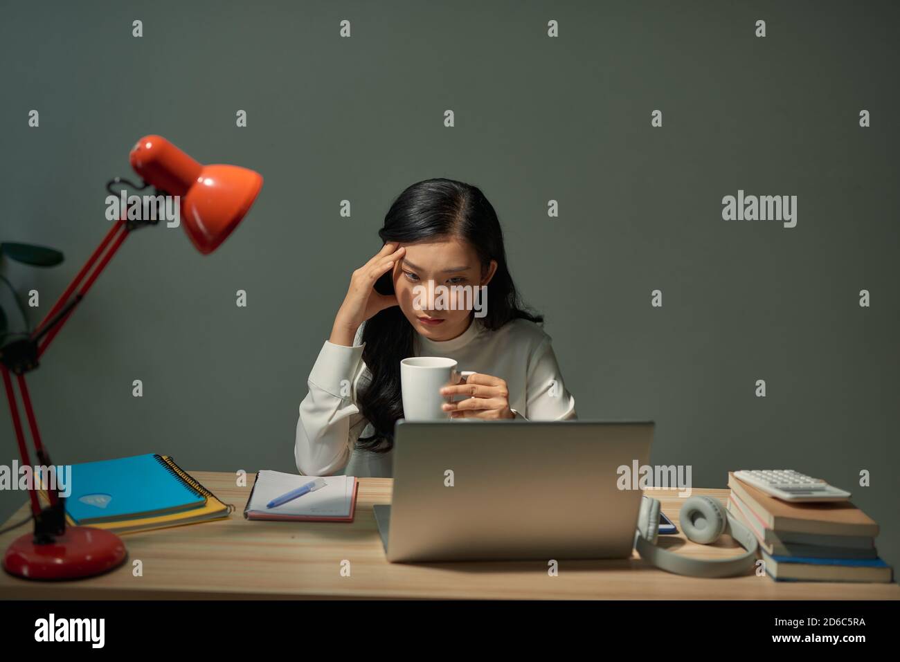 Pretty young student sitting at desk and doing her homework, she is ...