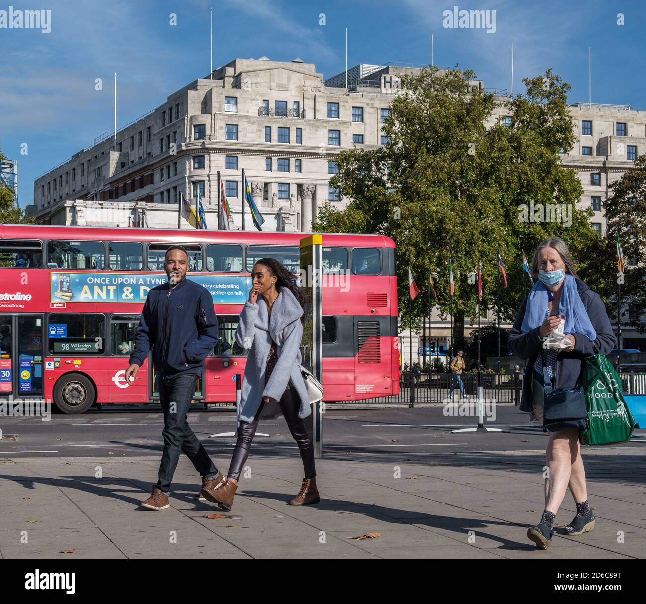 Lady in face mask with coffee & shopping bag & young couple walk ...