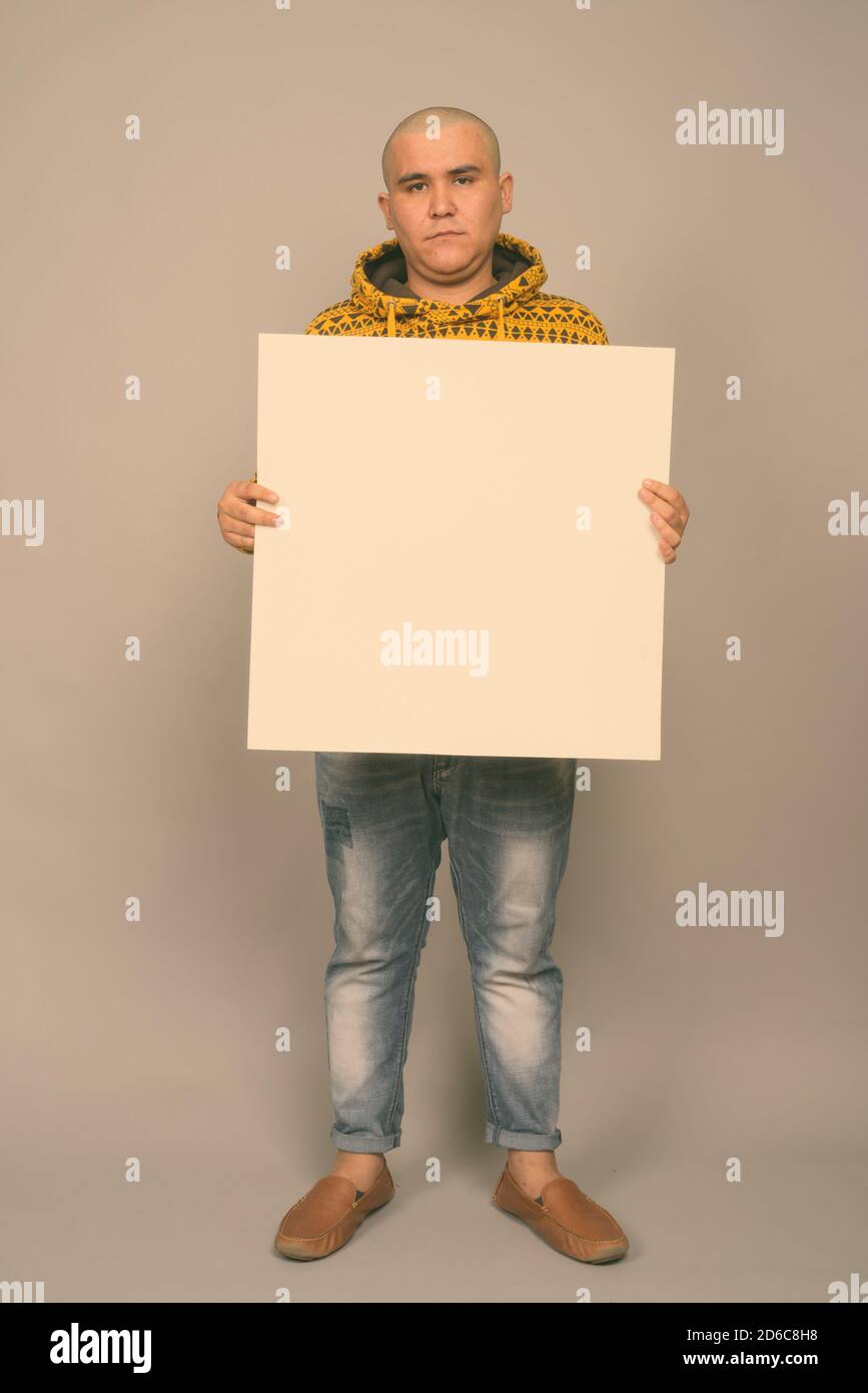 Young bald Asian man against gray background Stock Photo - Alamy