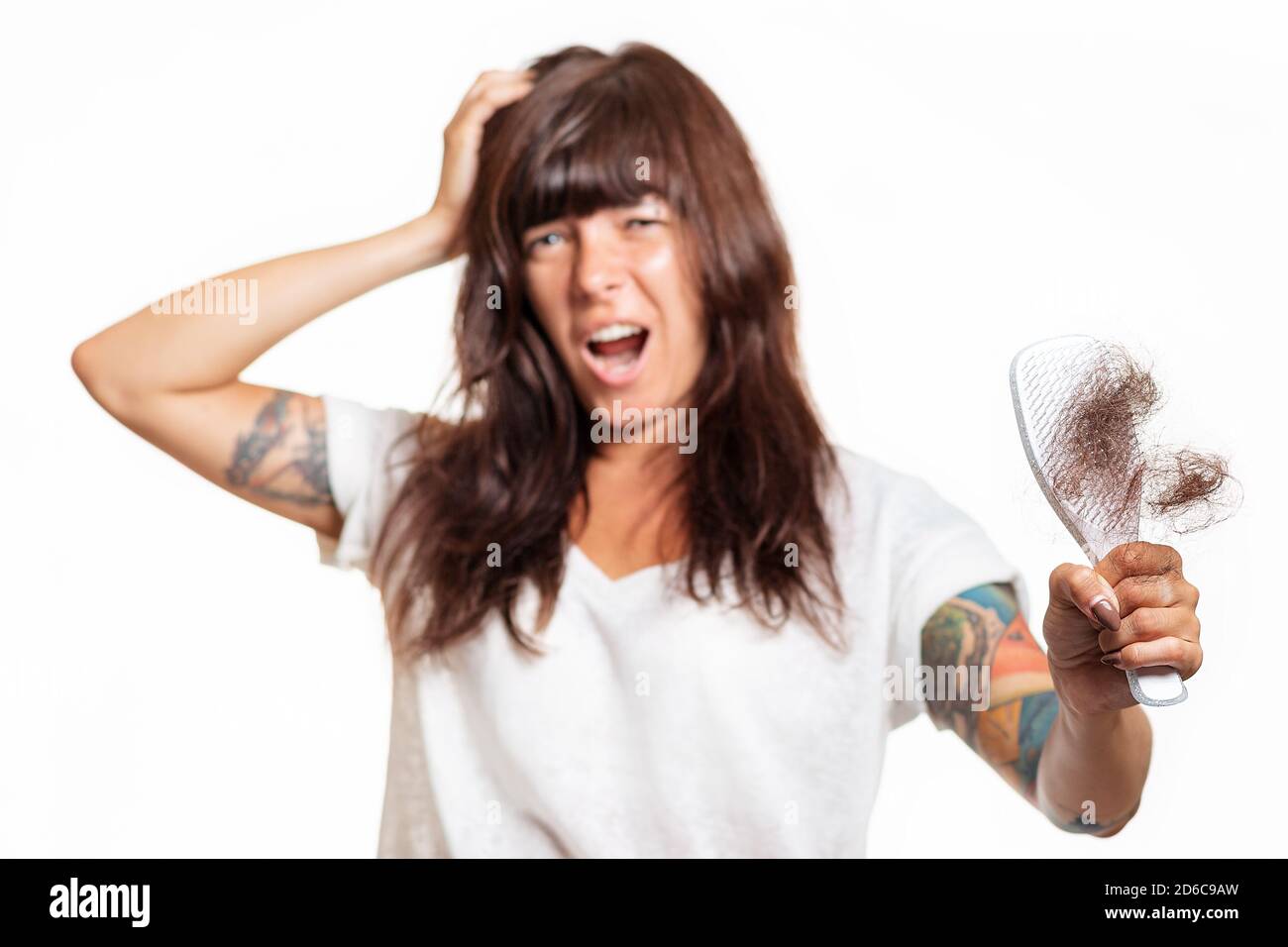A blurred portrait of tattooed woman holds a comb with her hair pulled ...