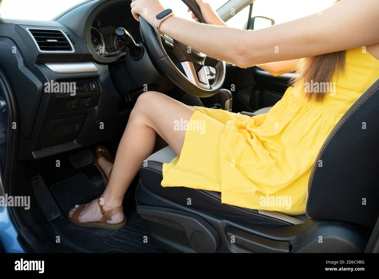 Young woman driver legs in yellow summer dress behind steering wheel ...