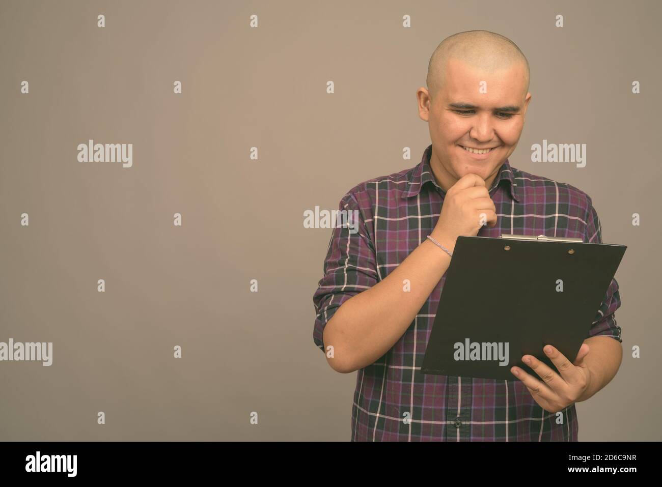 Young bald Asian businessman against gray background Stock Photo - Alamy