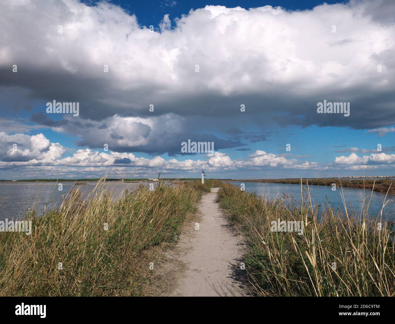 Photo of a path between two ponds with thick clouds in the sky Stock ...
