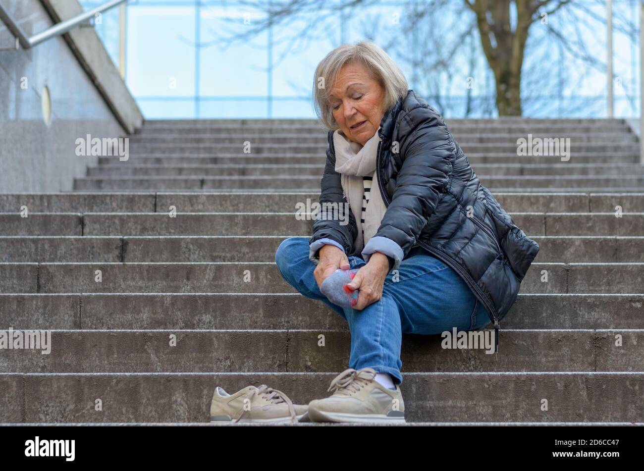 Helpless senior woman massaging her Foot to relive aches and pains ...