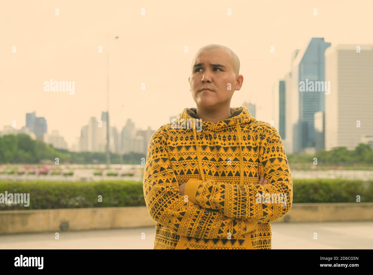 Young bald Asian man against view of the city at the park Stock Photo ...