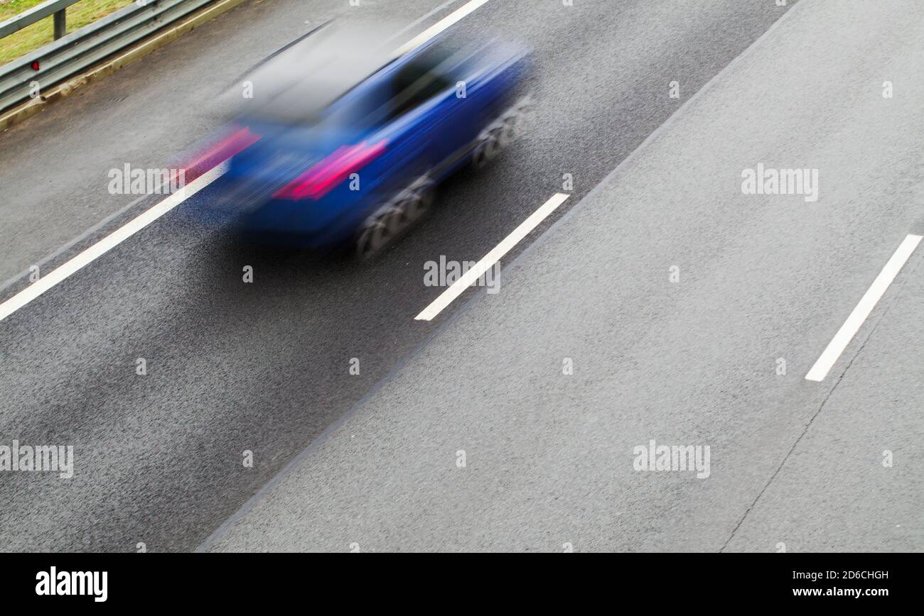 Blue blurred car is driving fast on the highway on a highway, abstract ...