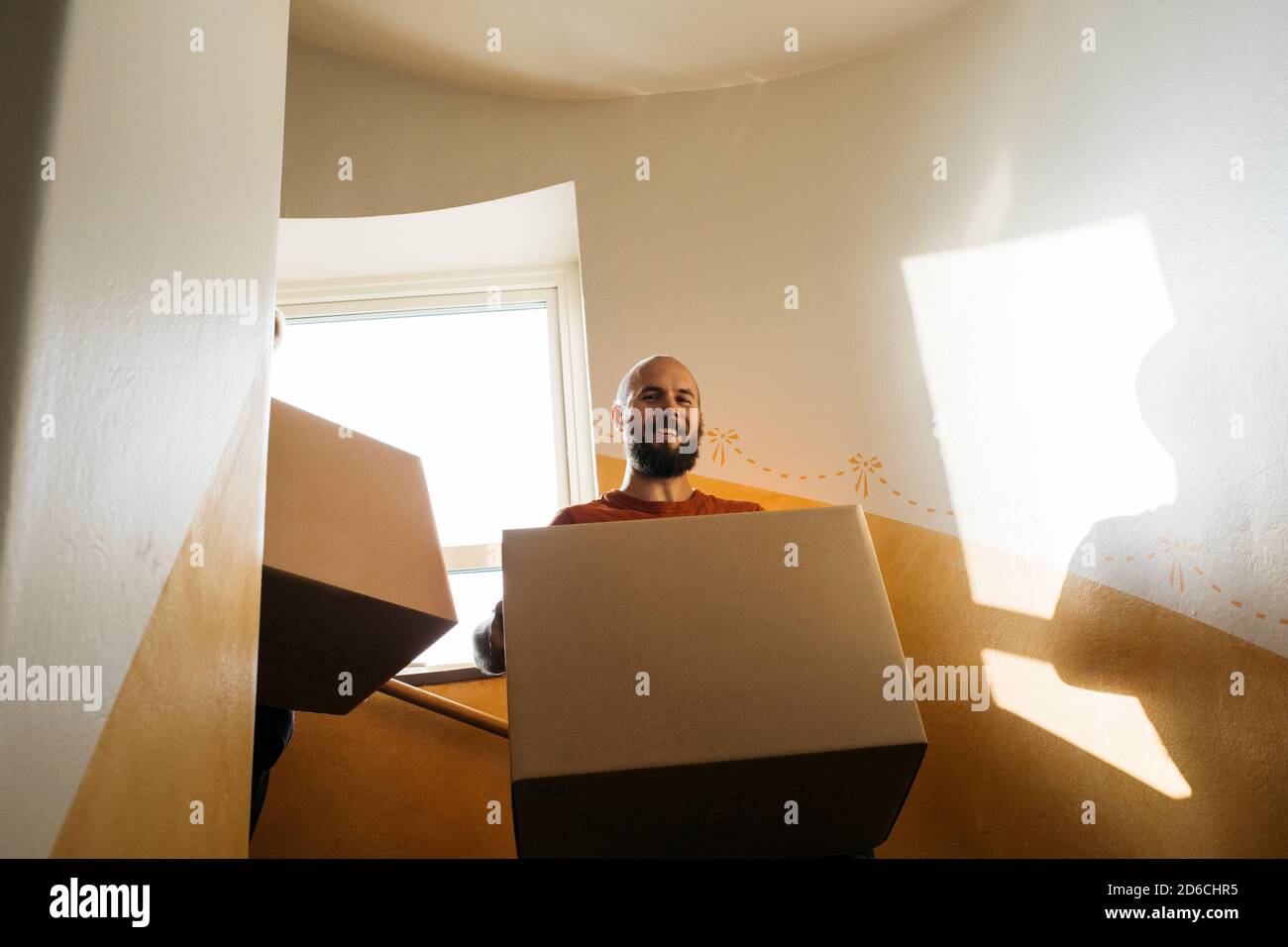 Man carrying cardboard box at staircase Stock Photo - Alamy