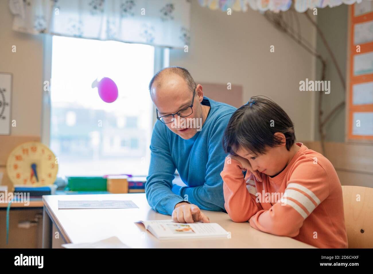 Teacher helping boy in classroom Stock Photo - Alamy