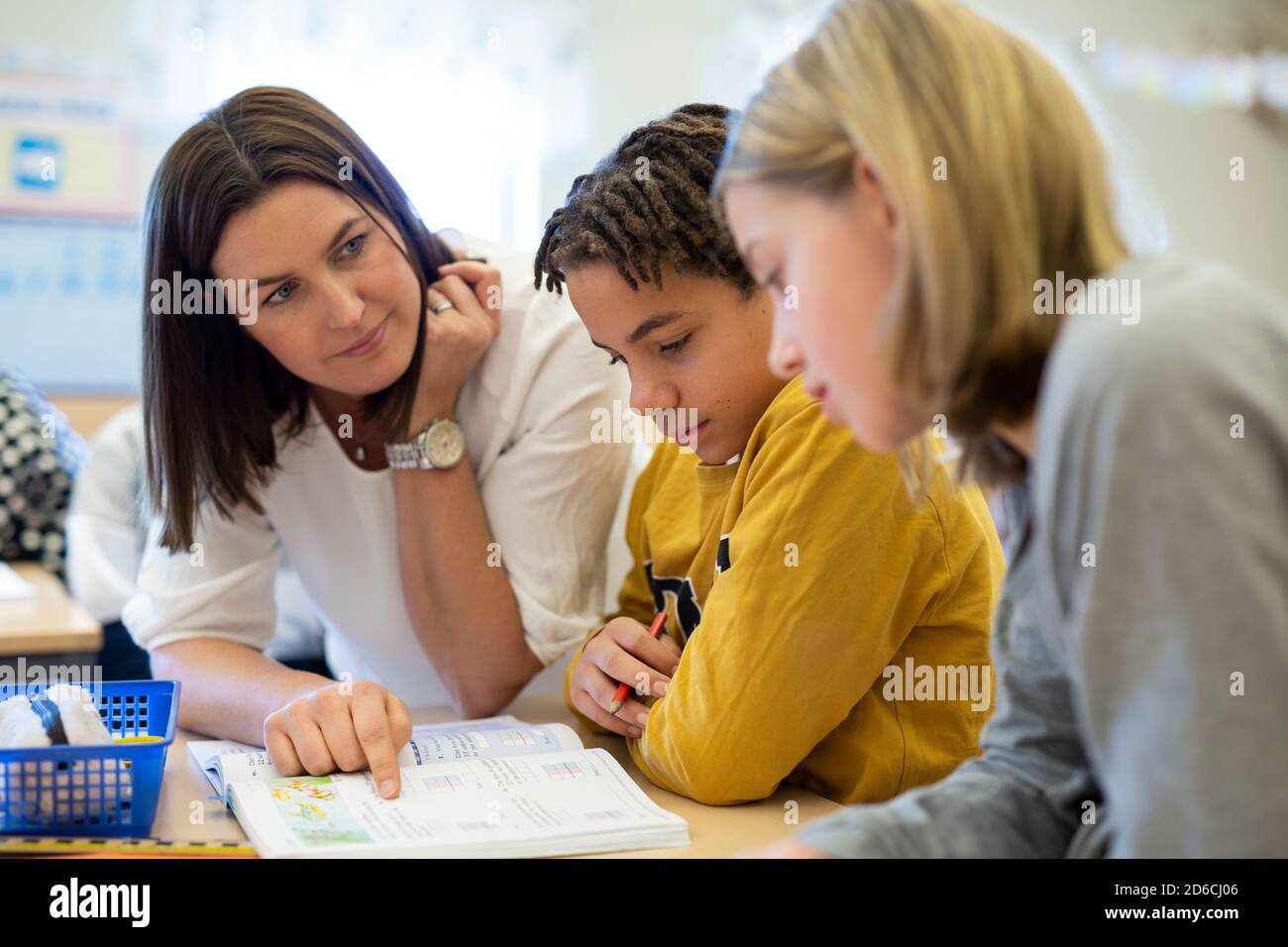 Teacher helping children in classroom Stock Photo - Alamy