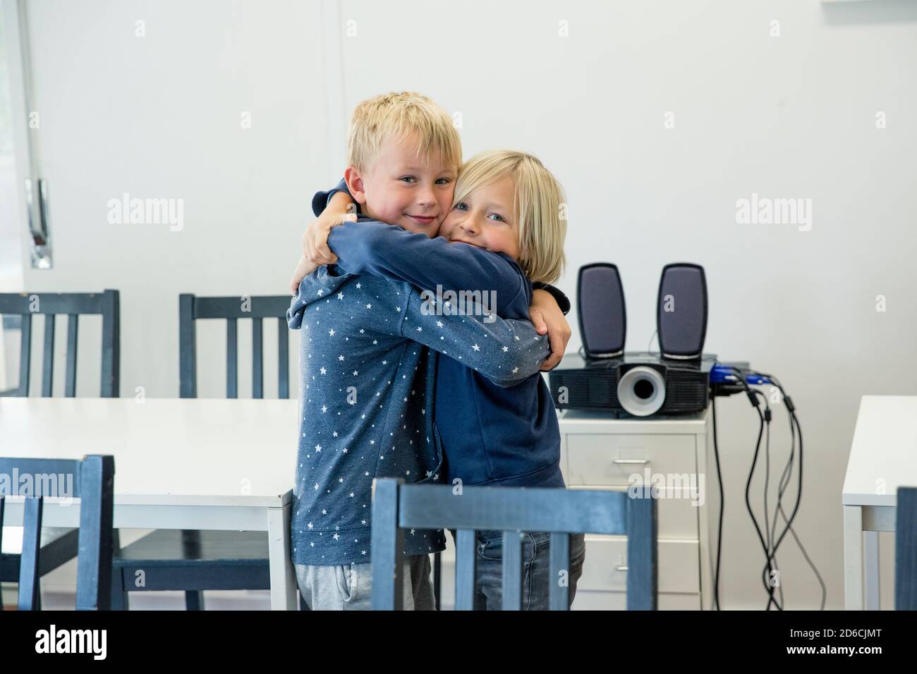 Boys hugging in classroom Stock Photo - Alamy