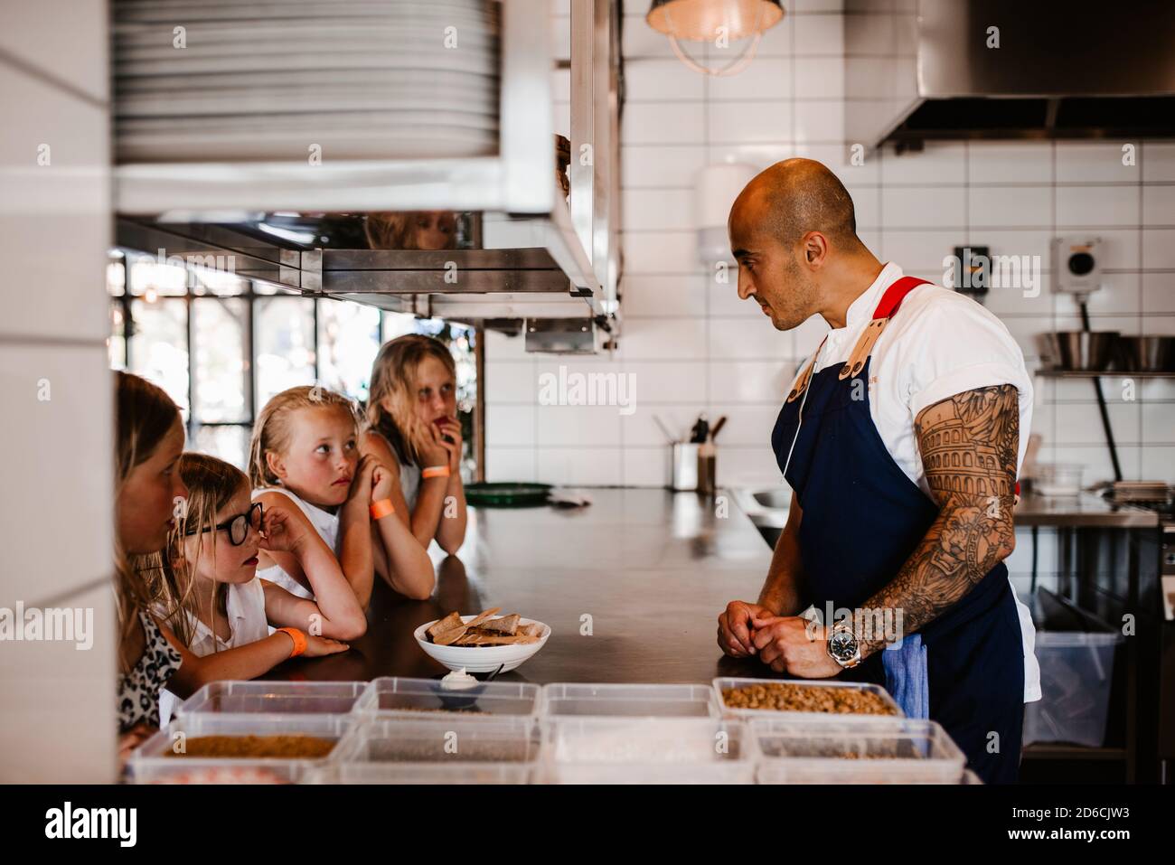 Girls watching chef working in restaurant kitchen Stock Photo - Alamy