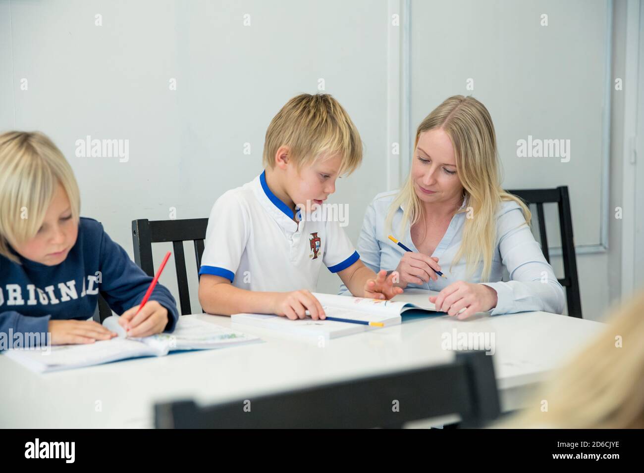 Teacher helping boy in classroom Stock Photo - Alamy