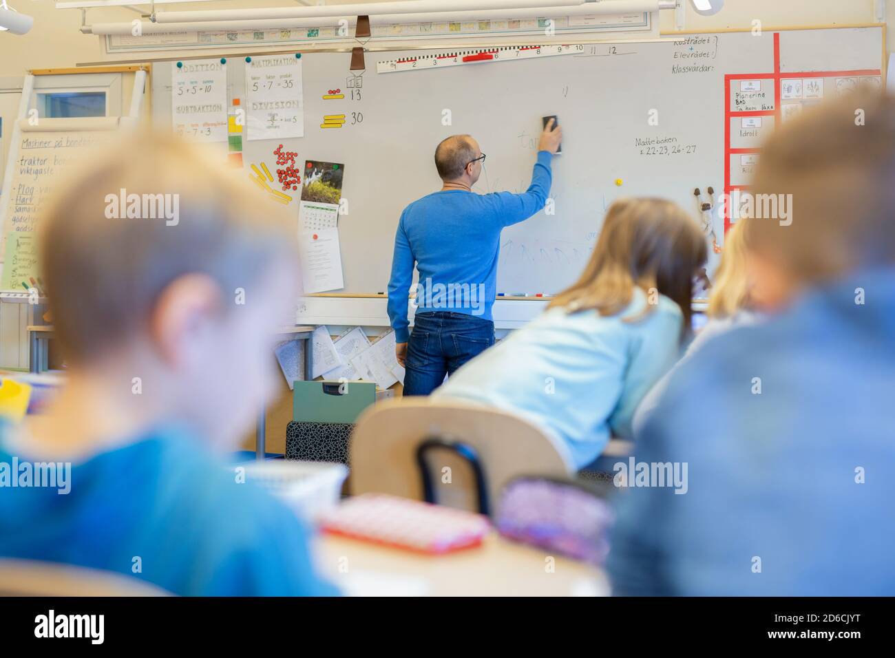 Teacher writing on whiteboard in classroom Stock Photo - Alamy